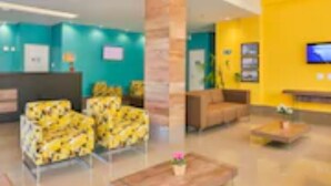 Um lobby moderno com balcão de recepção, área de estar e uma tela de televisão.