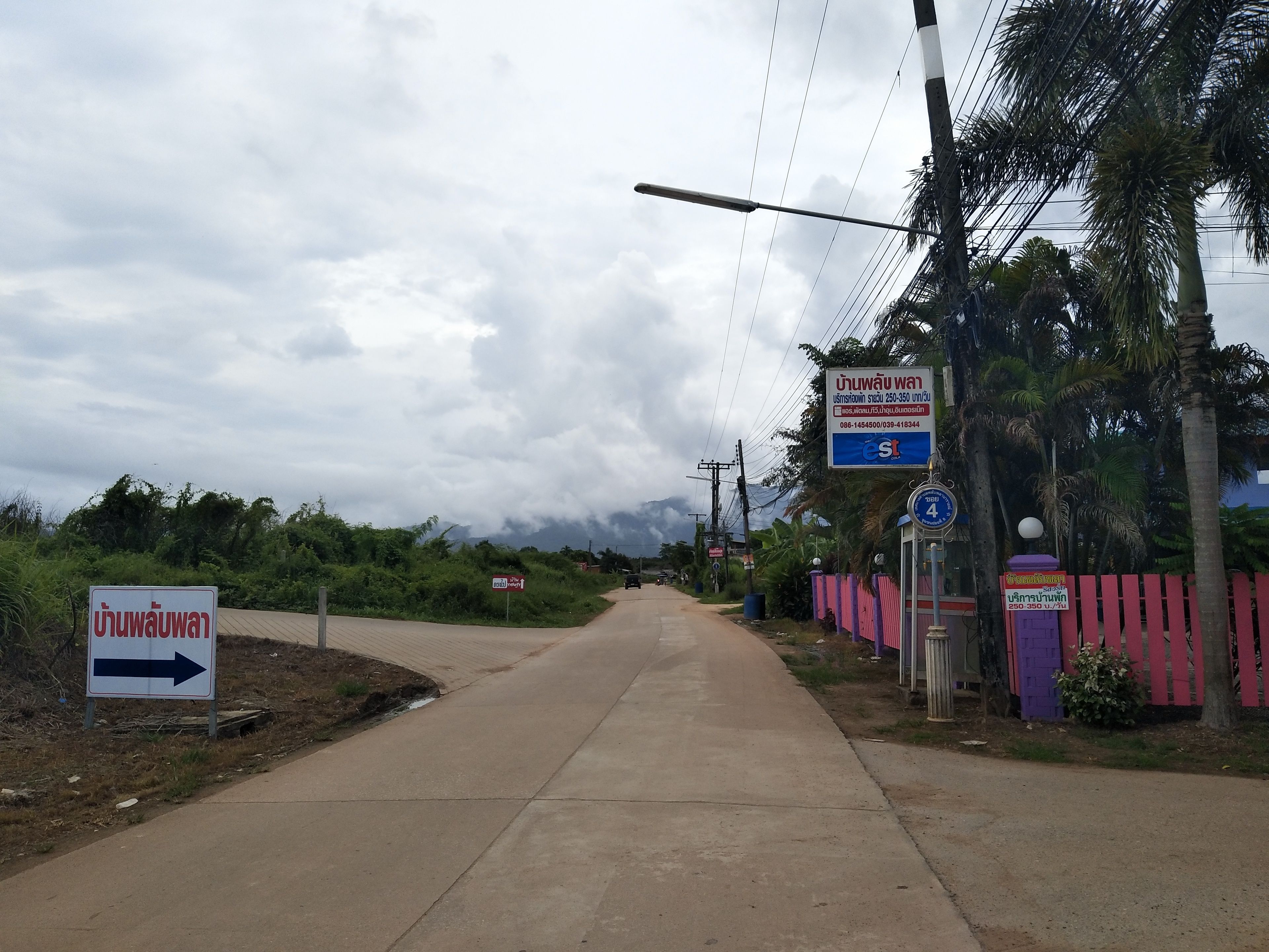Uma estrada com uma placa de direção e uma placa azul indicando uma rota.