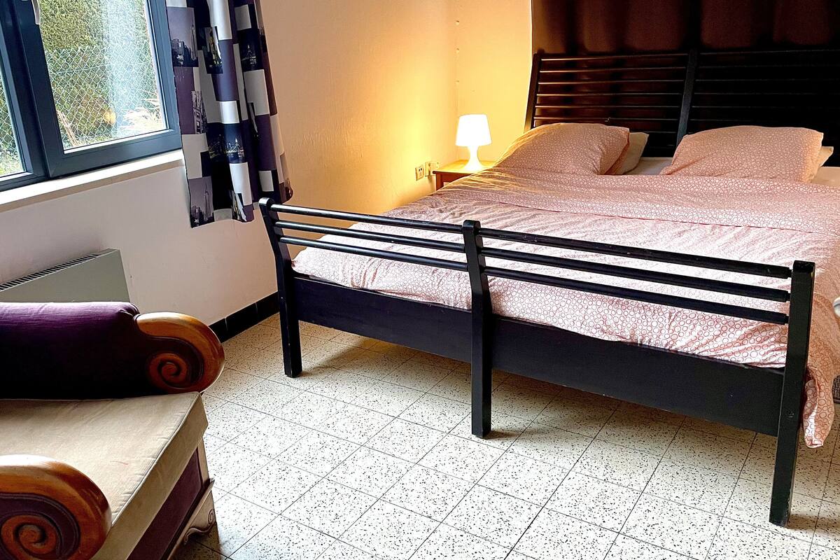Quarto com cama, cadeira, janela e abajur.
