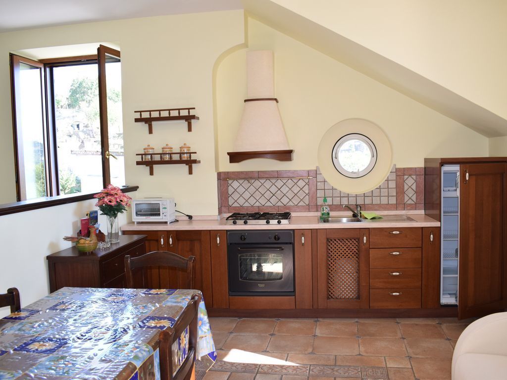 Cozinha com armários de madeira, fogão, forno e janela.