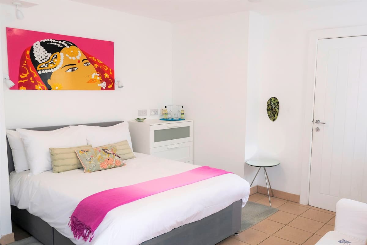 Quarto com cama, mesa de cabeceira e um quadro na parede.