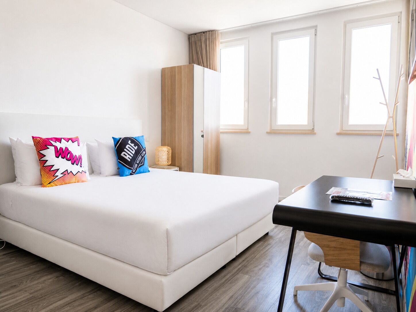 Quarto de hotel com uma cama, uma escrivaninha e um guarda-roupa.