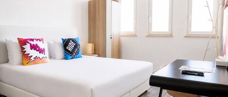 Quarto de hotel com uma cama, uma escrivaninha e um guarda-roupa.
