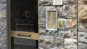Fachada de pedra com porta de vidro e placa de metal com o número 50.