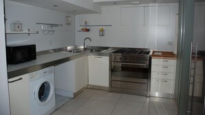 Uma cozinha moderna com máquina de lavar, fogão, pia e armários.