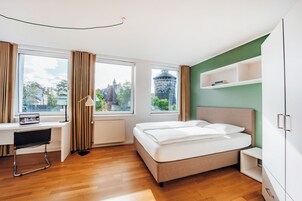 Quarto de hotel moderno com cama, escrivaninha e computador.