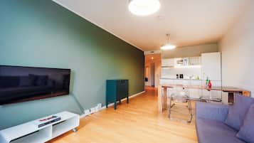 Uma sala de estar moderna com televisão de tela plana, sofá e área de jantar com mesa e cadeiras.