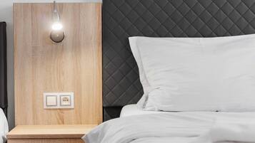 Quarto moderno com cabeceira de madeira, mesa de cabeceira e cama com roupa de cama branca.