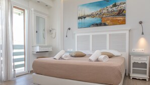 Quarto com cama, quadro, mesa de cabeceira e criado-mudo.