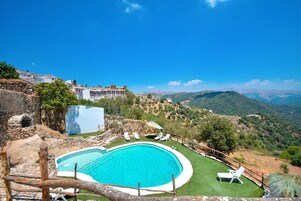 Piscina com vista para uma colina e um edifício ao fundo.