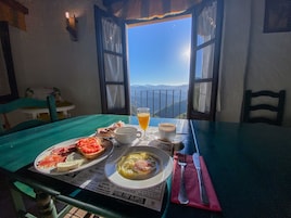 Uma mesa com itens de café da manhã, um jornal e um copo de suco de laranja.