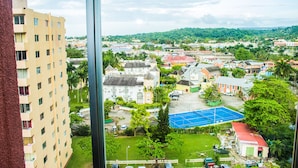 Uma área residencial com quadra de tênis, um parque arborizado e um edifício de vários andares.