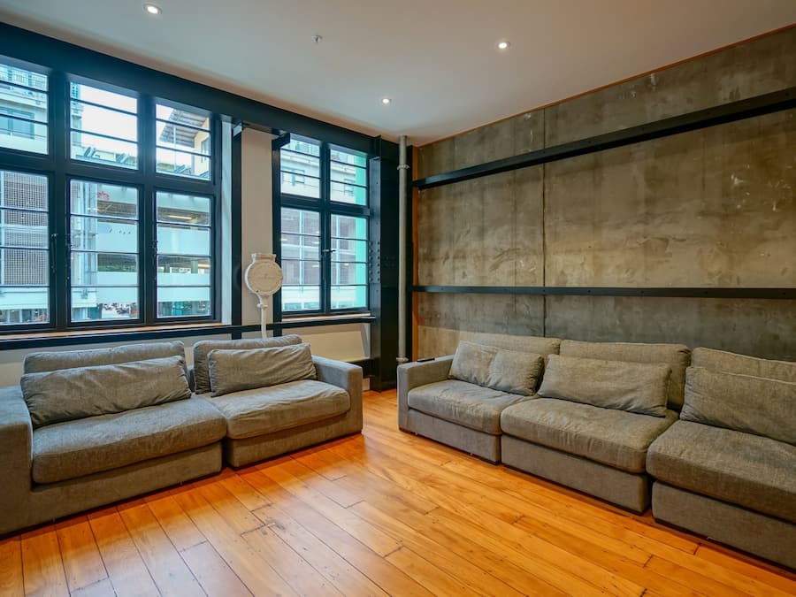 Uma sala de estar moderna com uma janela grande, um abajur branco e dois sofás cinzas.