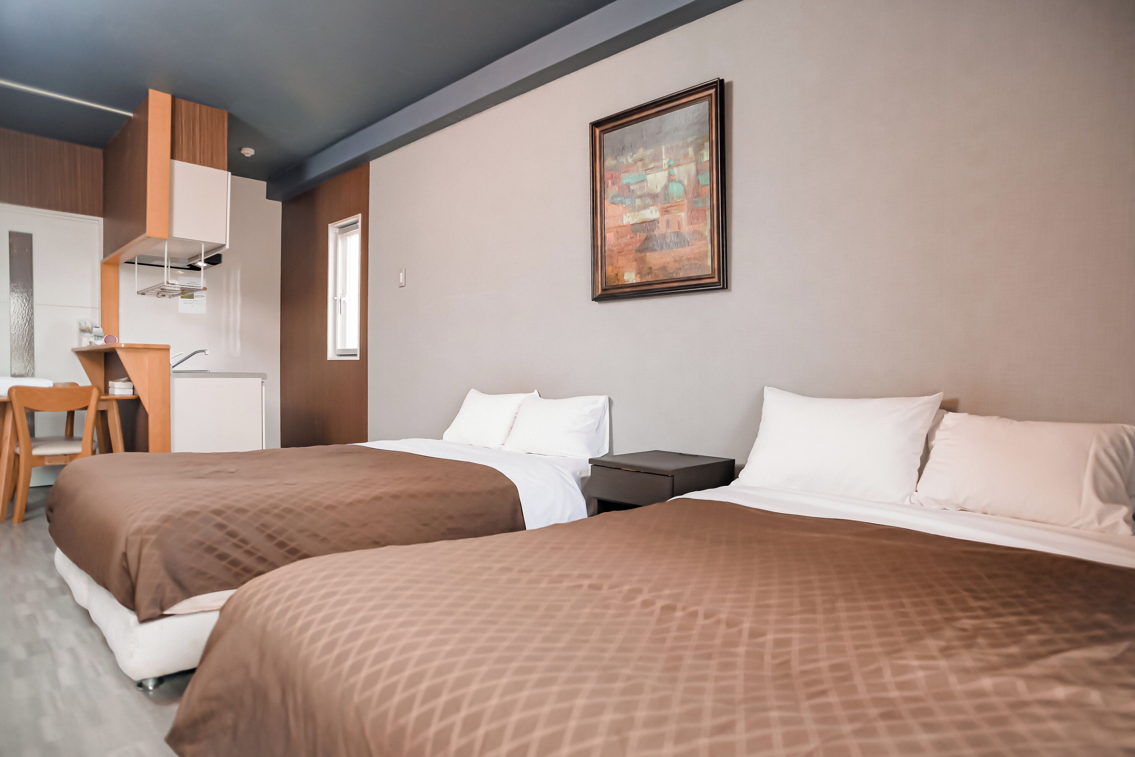 Quarto de hotel com duas camas, uma escrivaninha e uma cadeira.