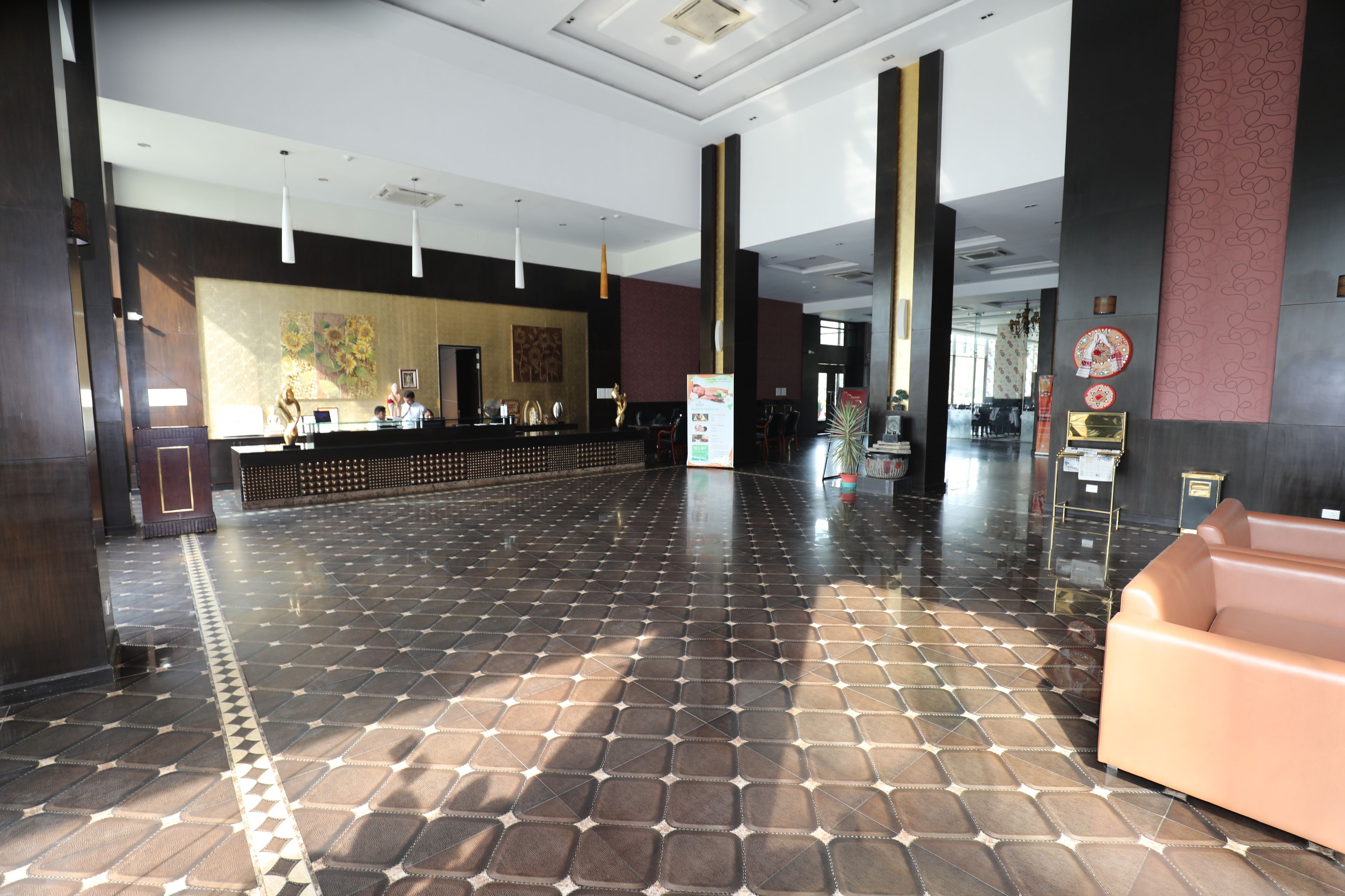 Um hall amplo com piso estampado, balcão de recepção e área de estar.