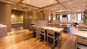 Um restaurante espaçoso com piso de madeira, diversas mesas e cadeiras, e um design moderno no teto.