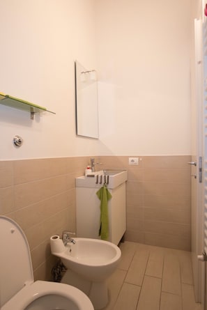 Uma casa de banho pequena com sanita, bidé e lavatório.