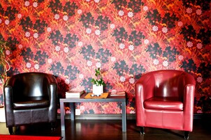 Duas poltronas de couro viradas uma para a outra, separadas por uma mesa, com um papel de parede floral ao fundo.