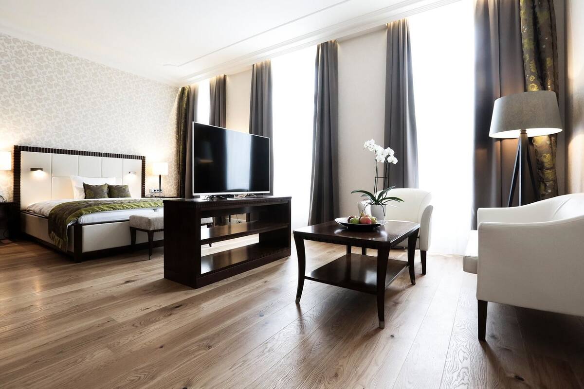 Quarto de hotel moderno com cama, televisão, escrivaninha e cadeira.