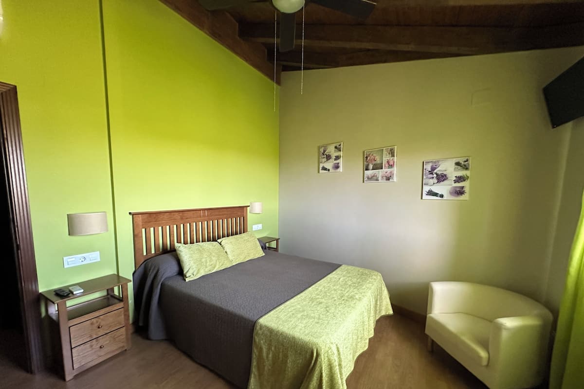 Quarto com cama, mesas de cabeceira, uma cadeira e decorações nas paredes.