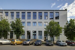 Um edifício moderno com várias janelas e um estacionamento com diversos carros.