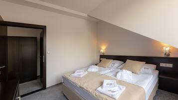 Quarto de hotel com cama, guarda-roupa e mesa de cabeceira com abajur.