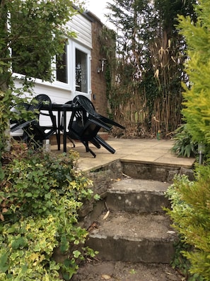 Um jardim com escadas que levam a um edifício branco, rodeado por vegetação e bambu.