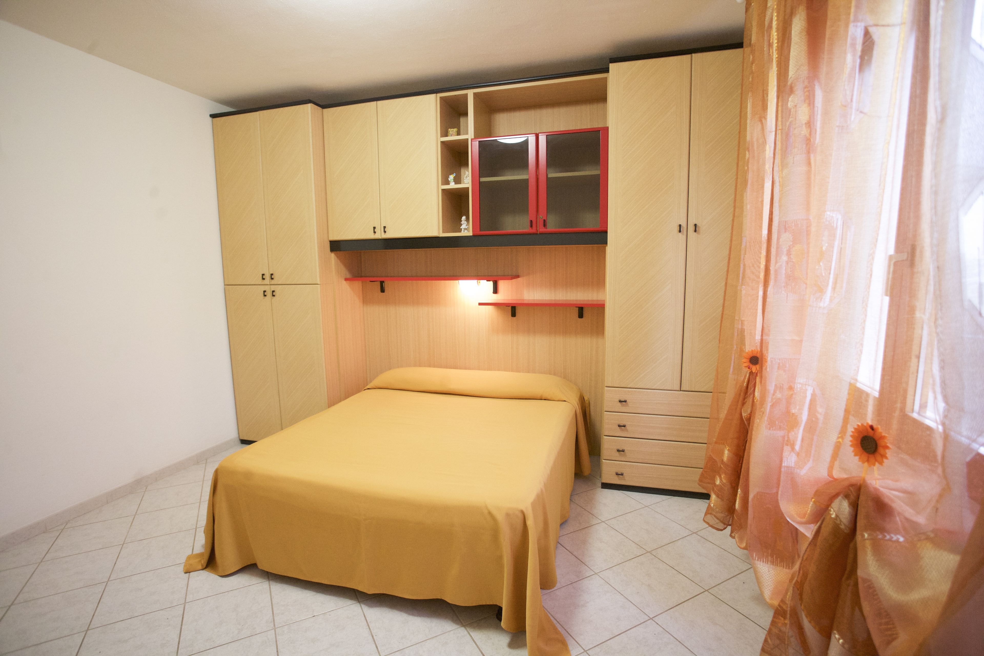 Quarto com cama, guarda-roupa e estante.