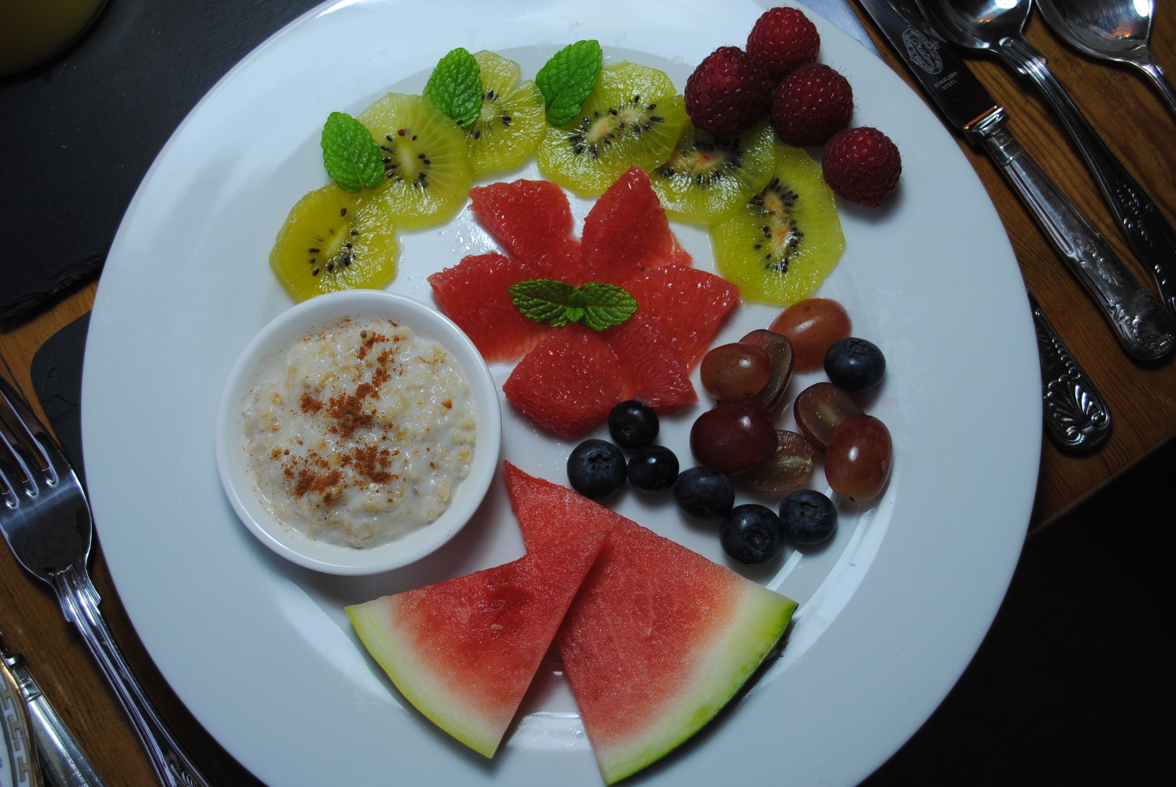 Um prato com diversas frutas e uma pequena tigela de sobremesa.