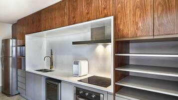 Cozinha moderna com armários de madeira, eletrodomésticos de aço inoxidável e prateleiras embutidas.