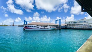 Um barco atracado em um cais, com um céu azul límpido e um prédio ao fundo.