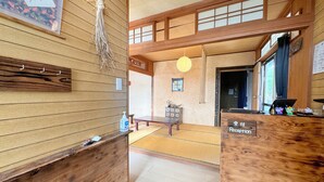 Uma área de recepção em estilo tradicional japonês, com paredes de madeira, piso de tatame e balcão de recepção.