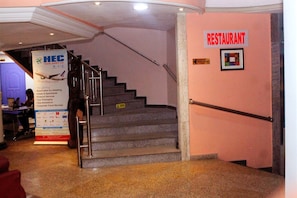 Escadaria que leva a uma área de restaurante, com uma placa indicando o local.