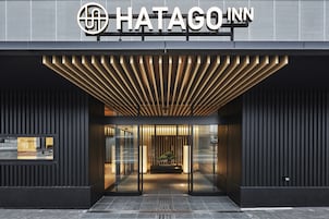 Exterior do Hatago Inn com design moderno, destacando uma entrada imponente com ripas verticais de madeira e fachada de vidro.