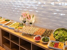 Uma mesa de buffet com diversos alimentos e um arranjo decorativo de flores brancas.