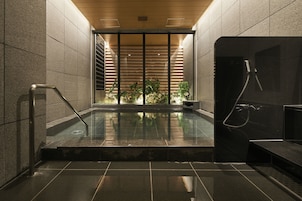 Uma área interna de piscina moderna com barreira de vidro, chuveiro e vista para o verde através das paredes de vidro.
