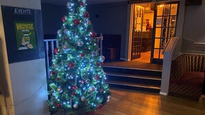 Árvore de Natal decorada com enfeites e luzes em um saguão de hotel.