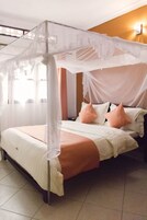 Uma cama com dossel, almofadas e mesa de cabeceira.