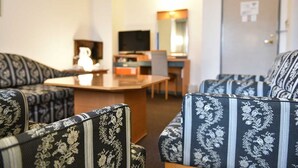 Uma sala de estar com sofás estampados, uma mesa de centro e uma televisão ao fundo.