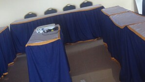 Uma sala de conferências com teto de madeira, um quadro branco e uma mesa com toalha azul.