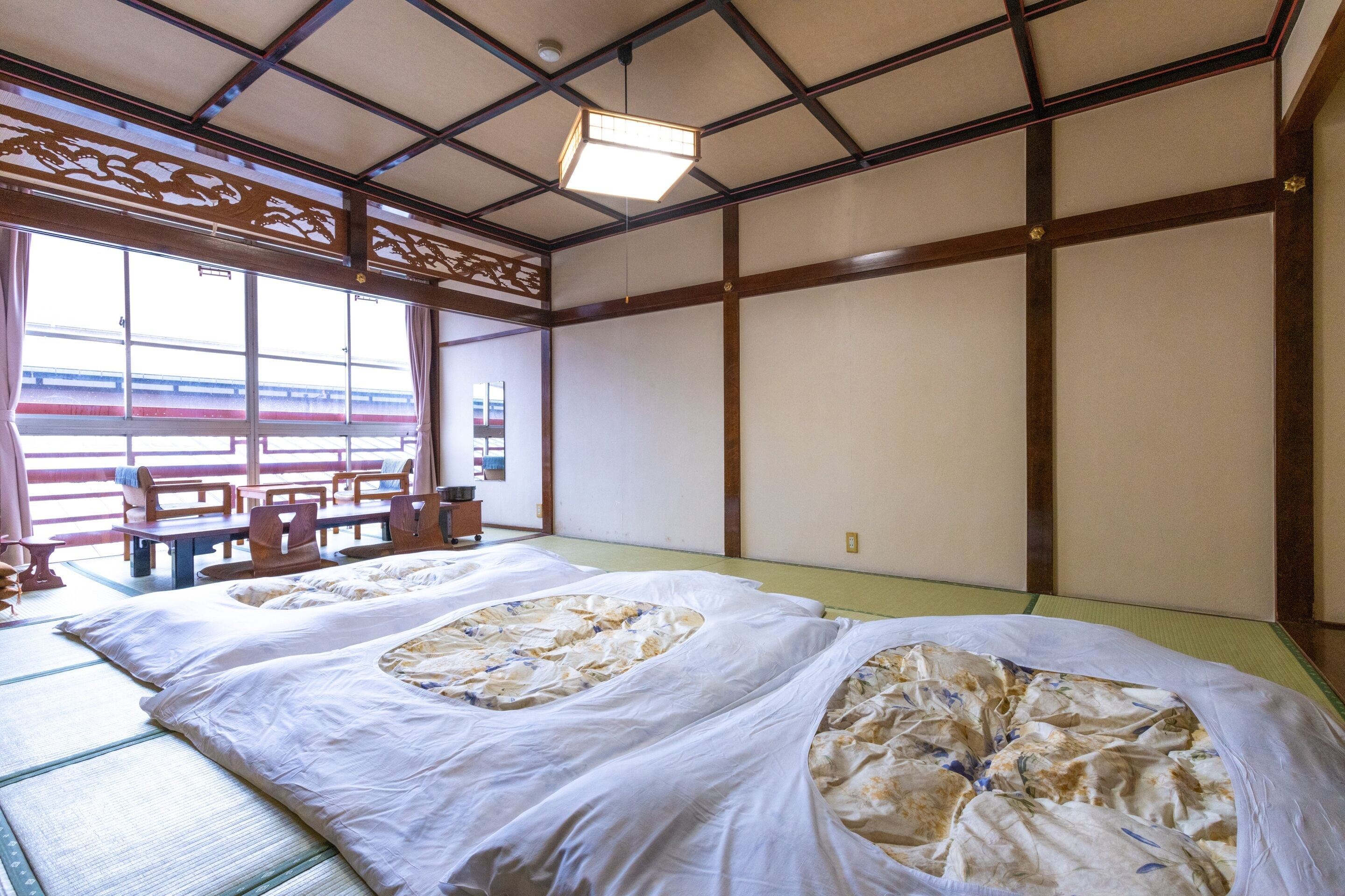 Um quarto japonês tradicional com esteiras de tatame, um biombos shoji e uma cama futon.