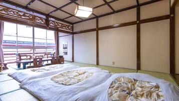 Um quarto japonês tradicional com esteiras de tatame, um biombos shoji e uma cama futon.
