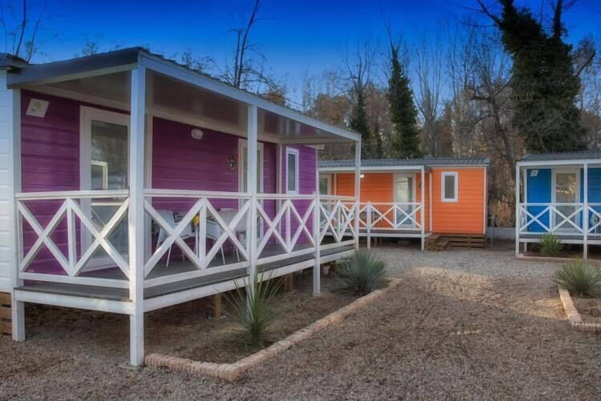 Uma fileira de casas móveis coloridas com guarda-corpos brancos, cada uma com uma pequena varanda.