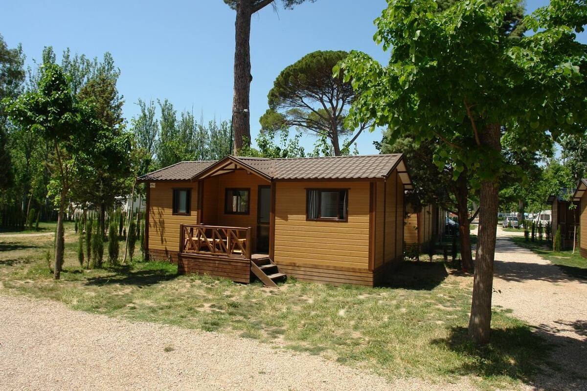 Uma pequena cabana de madeira com varanda e degraus que levam à entrada.