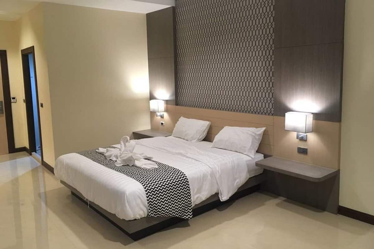 Quarto de hotel moderno com uma cama grande, duas mesas de cabeceira e um painel de cabeceira estampado.