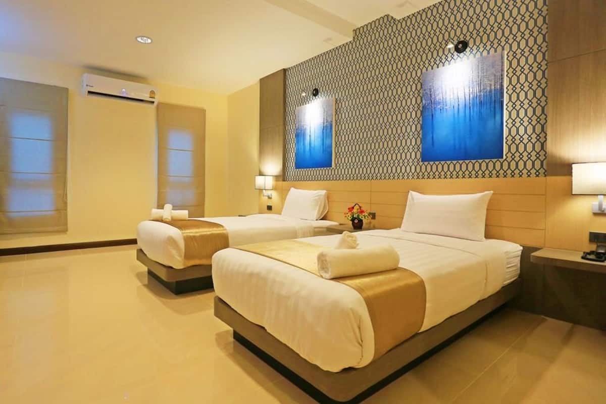 Quarto de hotel com duas camas, um papel de parede estampado e uma janela grande.