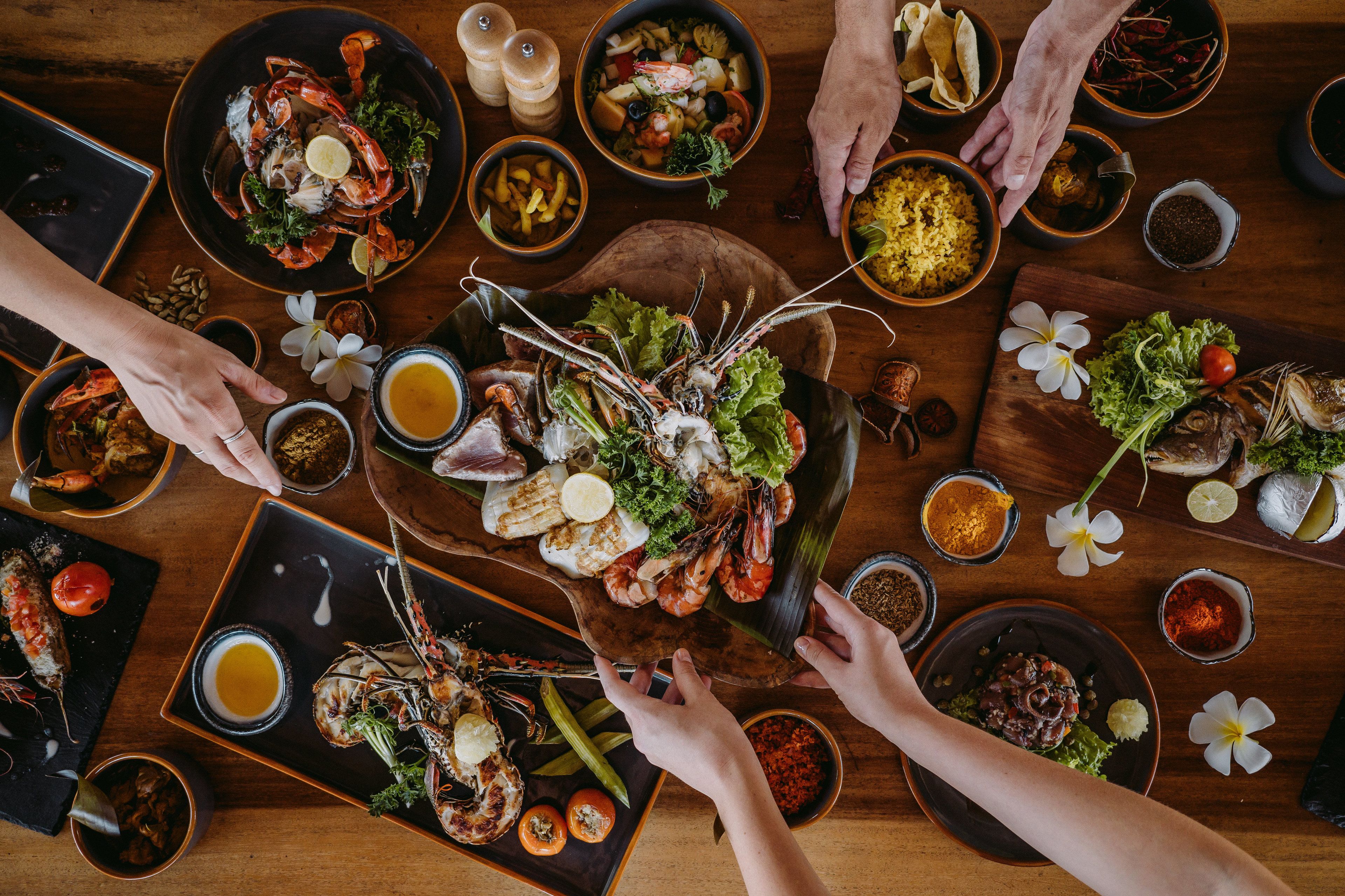 Uma mesa de jantar com diversos pratos de frutos do mar, acompanhamentos e um arranjo central de mariscos.