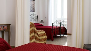 Quarto com duas camas, uma cadeira, uma mesa e uma janela.