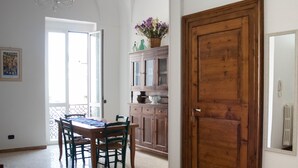 Uma sala de jantar com mesa e cadeiras de madeira, um armário com portas de vidro e uma grande porta de madeira.