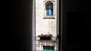 Visão através de uma porta para um prédio com janela e varanda florida.